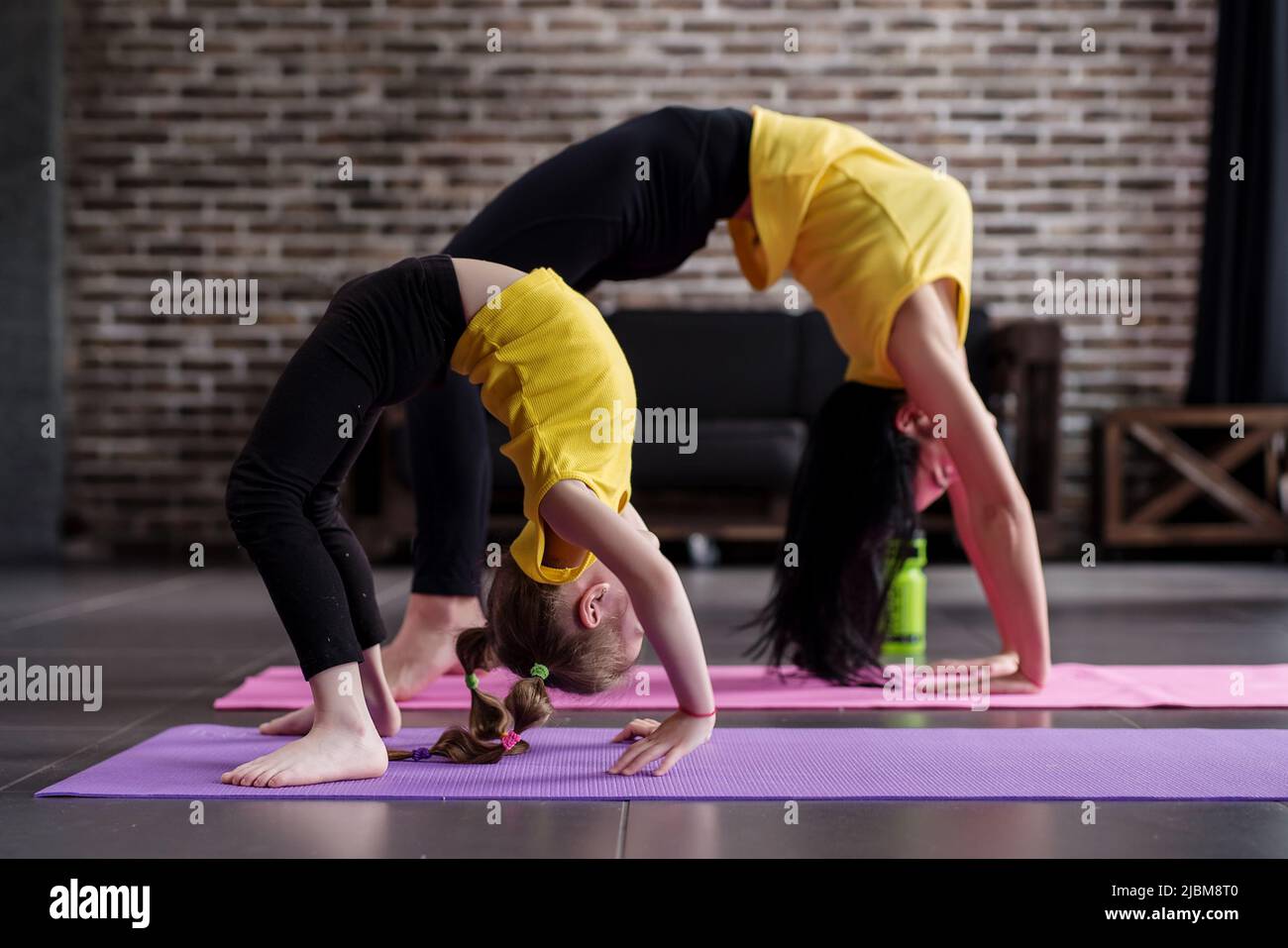 Two flexible girls of different age doing upward facing bow yoga pose ...