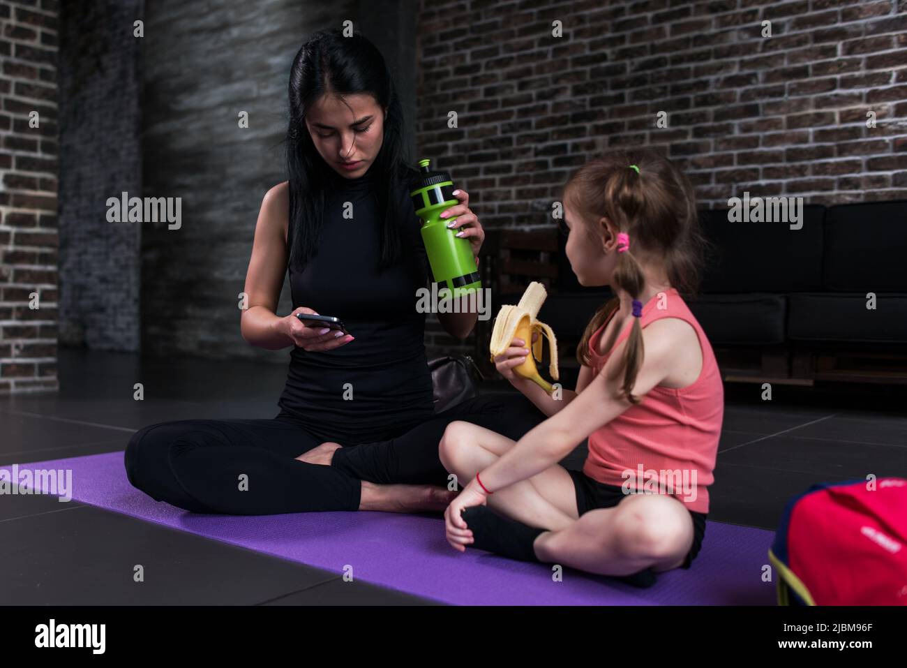 Yoga kid instructor and a girl having a break after workout sitting on ...