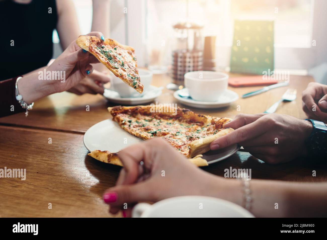 Close-up image of friends sharing traditional Italian pizza and ...