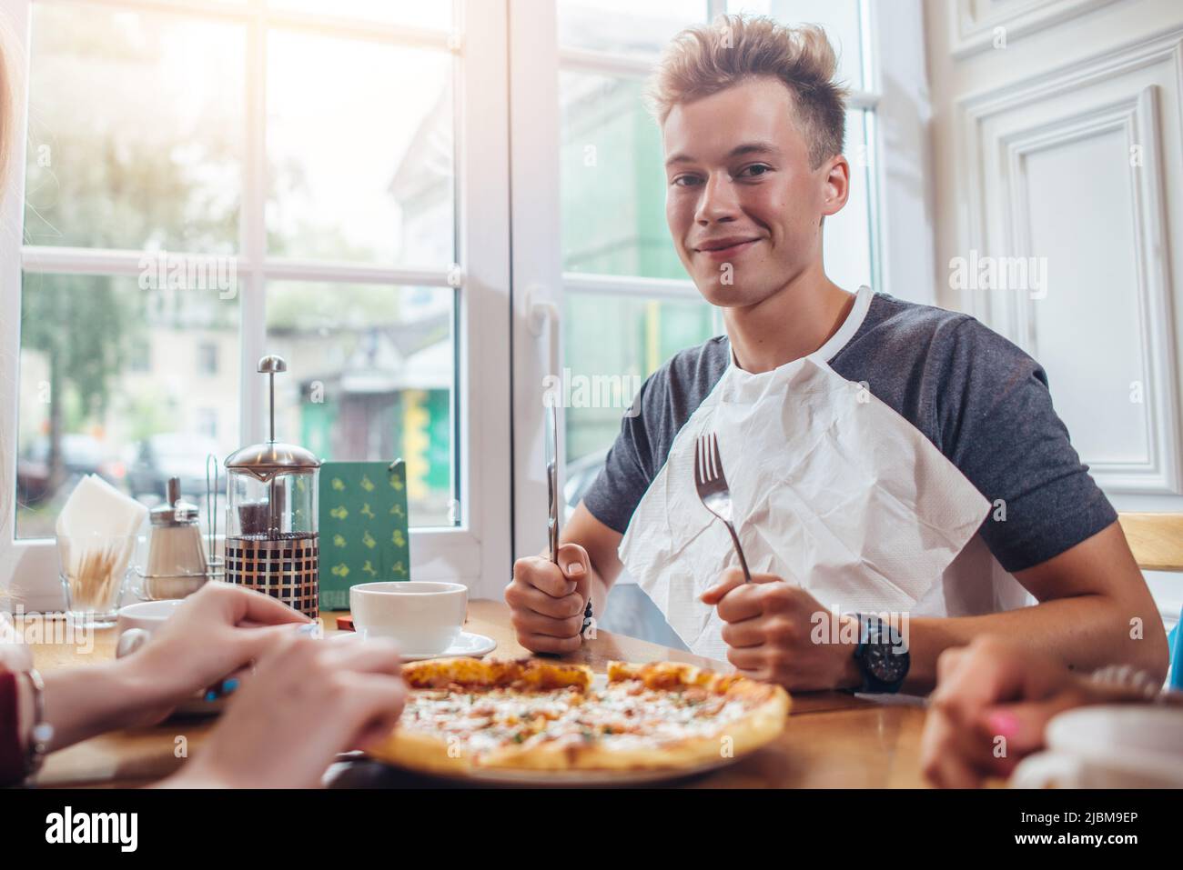 Stylish teenager wearing napkin holding knife and fork ready to eat ...