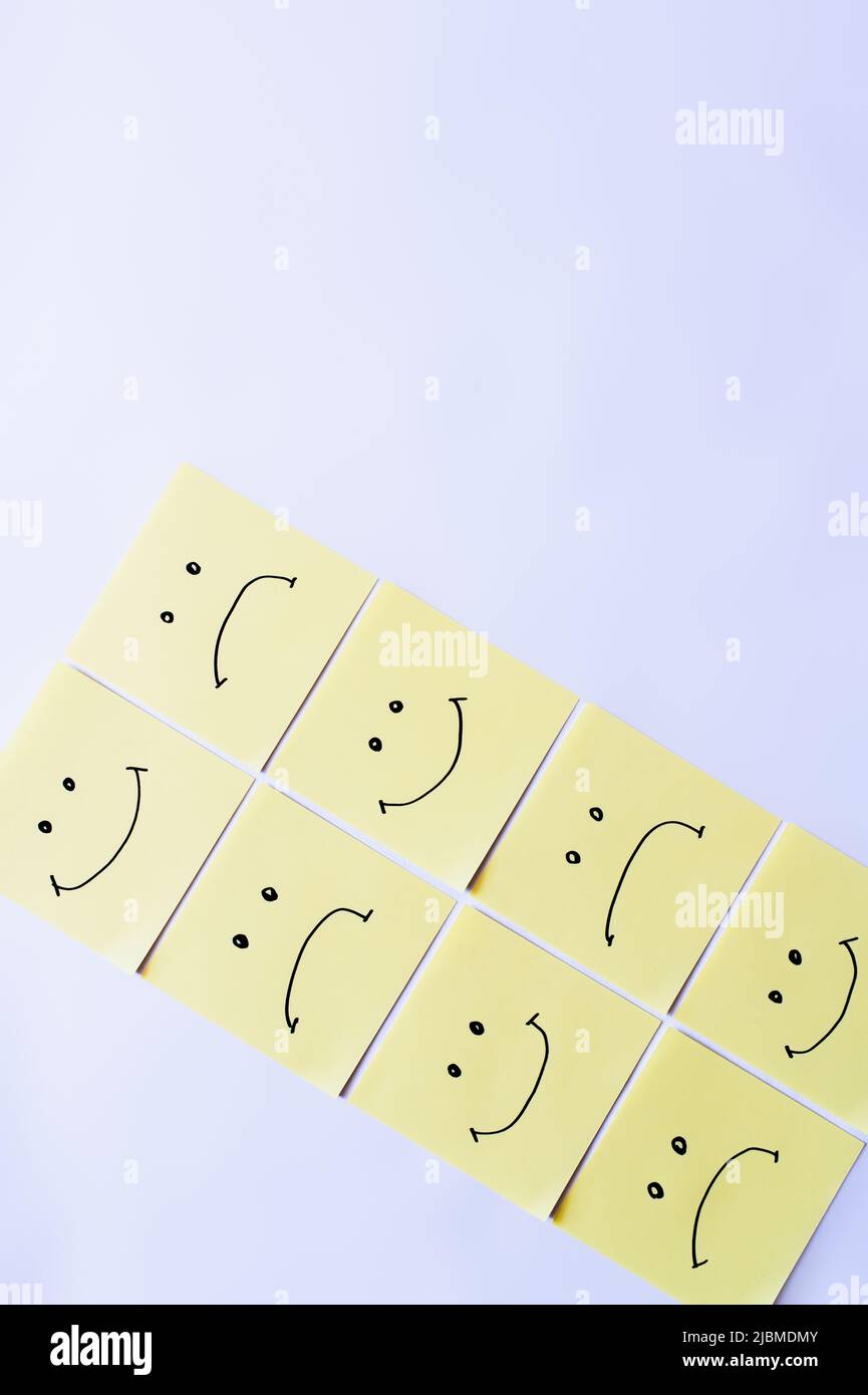 top view of pale yellow sticky notes with happy and upset emoji on ...