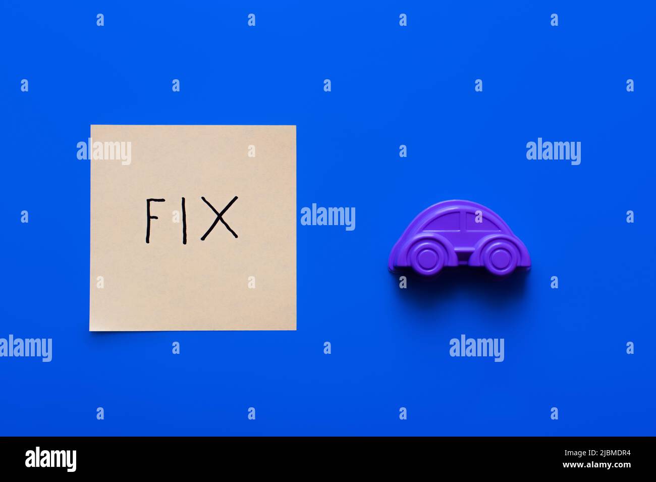 top view of purple plastic car near card with fix lettering on blue ...
