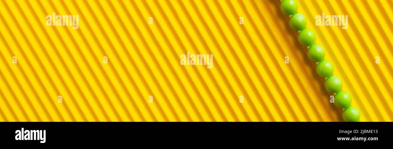 top view of small green balls on striped yellow background with copy ...