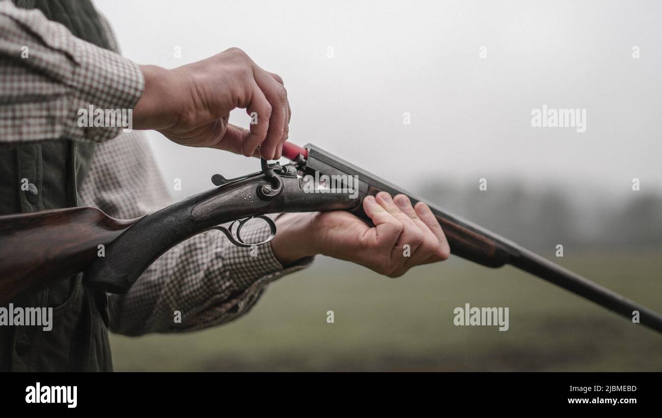Close-up of hunter man charges the cartridge on rifle gun in forest ...