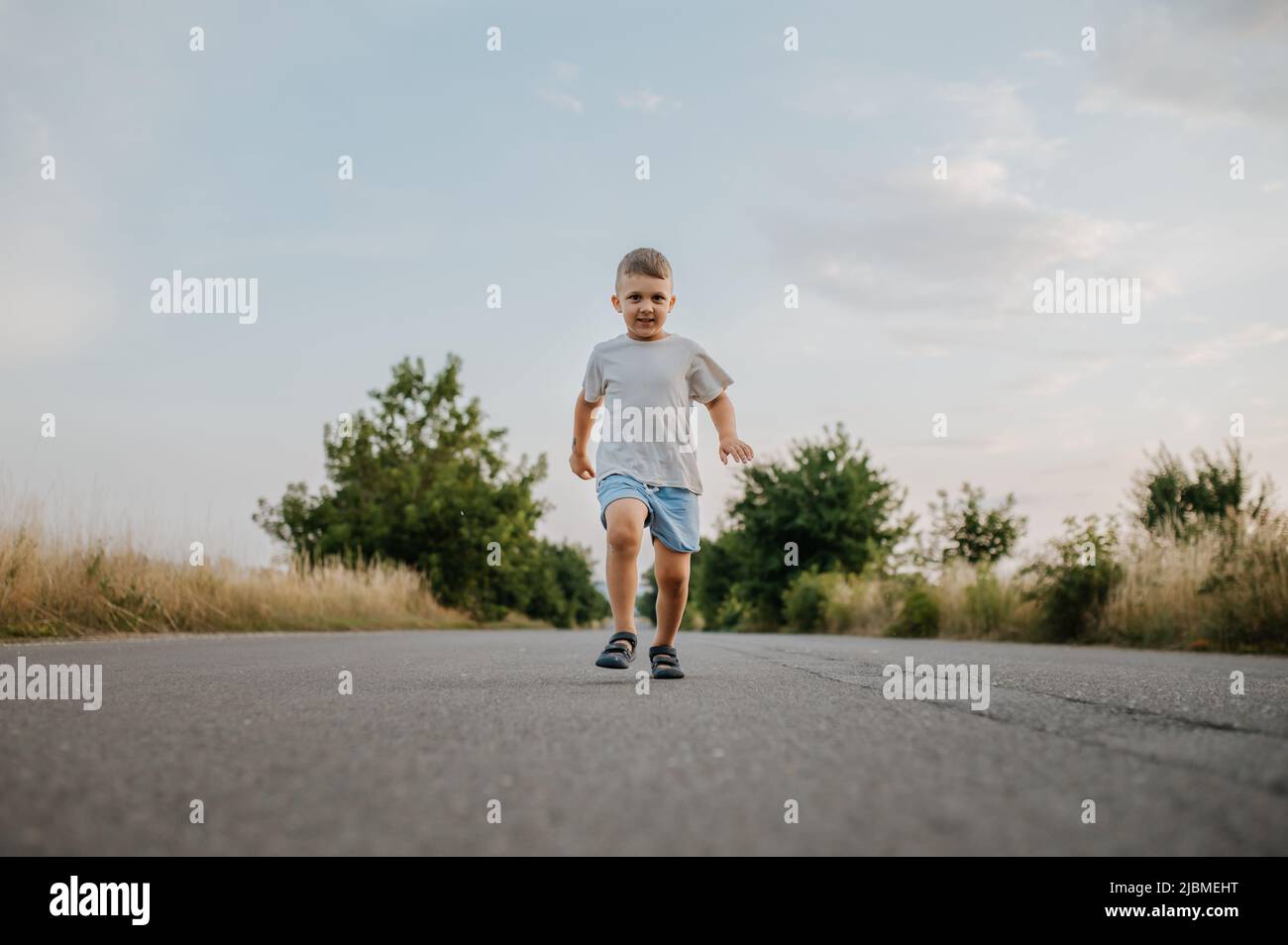 Little boy is running on road in summer Stock Photo - Alamy