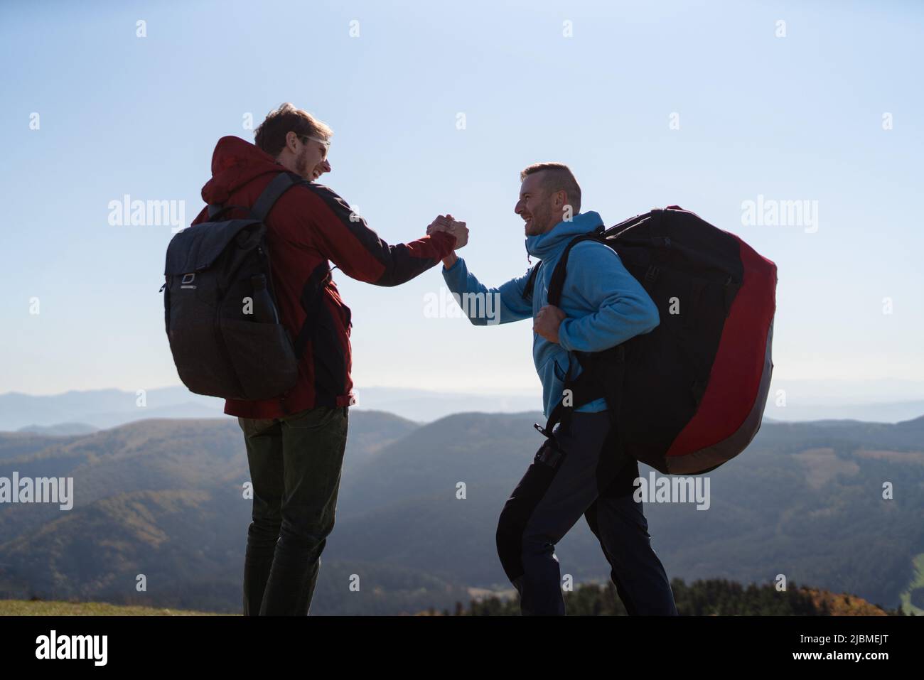 Paragliders high fiving after walking up hill to paragliding starting ...