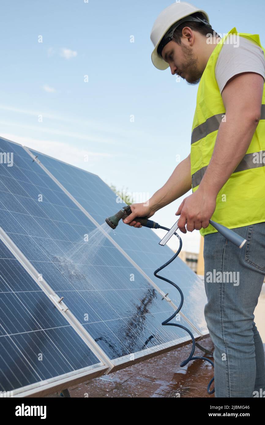 Technician cleaning solar panels with a hose Stock Photo - Alamy