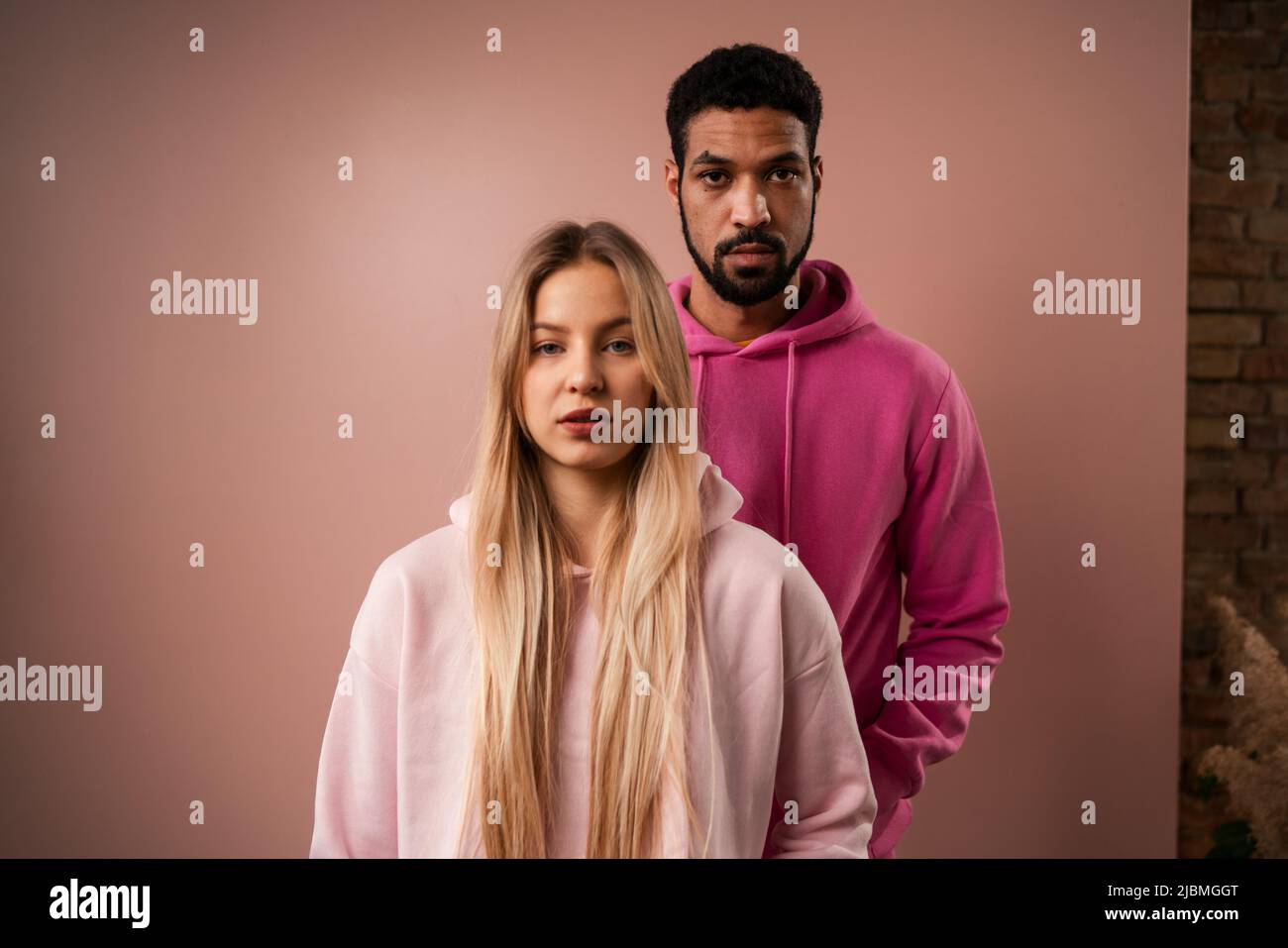 Fashion studio portrait of a happy young couple in hoodie posing over ...