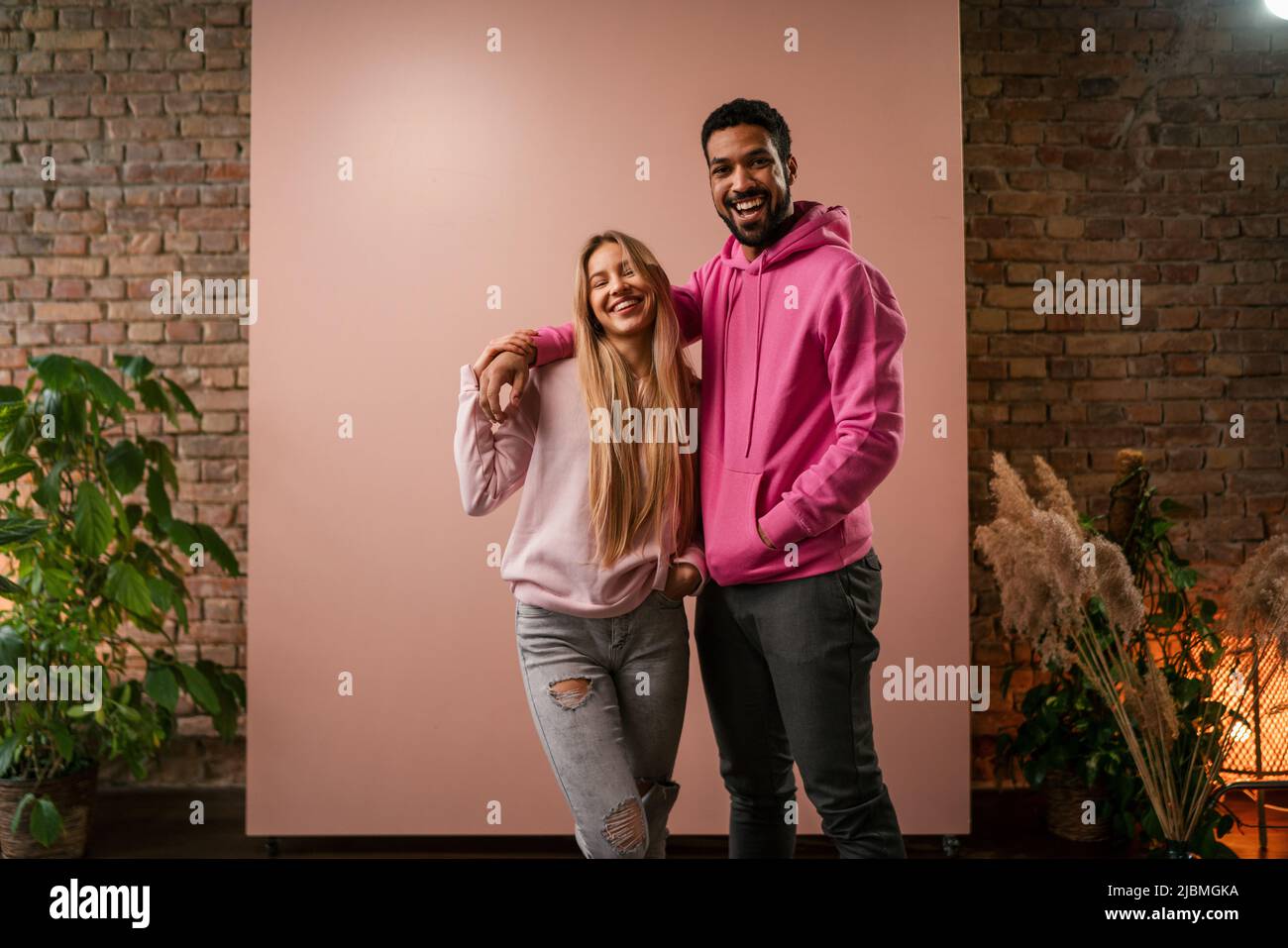 Fashion studio portrait of a happy young couple in hoodie posing over ...
