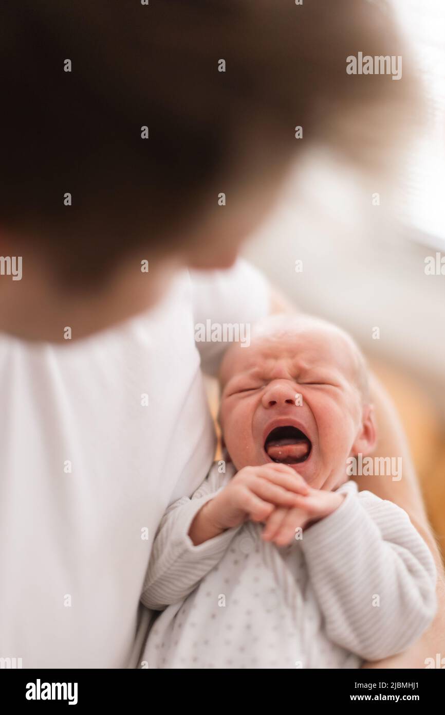Father holding his crying newborn son at home Stock Photo - Alamy