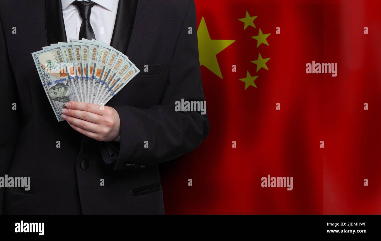 Chinese business man showing 100 US dollar bills against flag of China ...