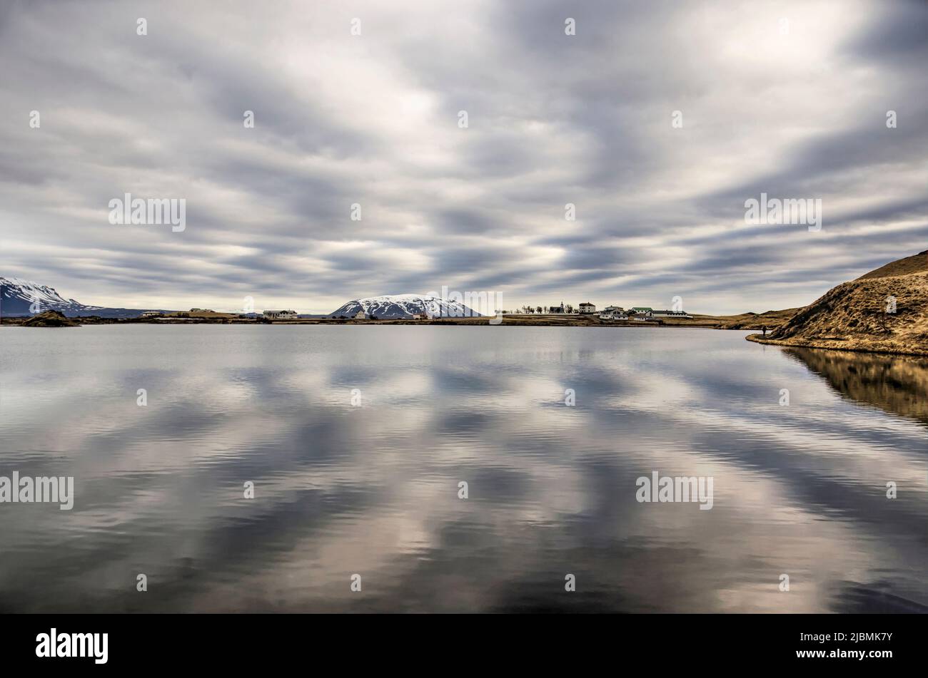 Dramatic overcast sky with bands of clouds reflecting in a lake in the ...