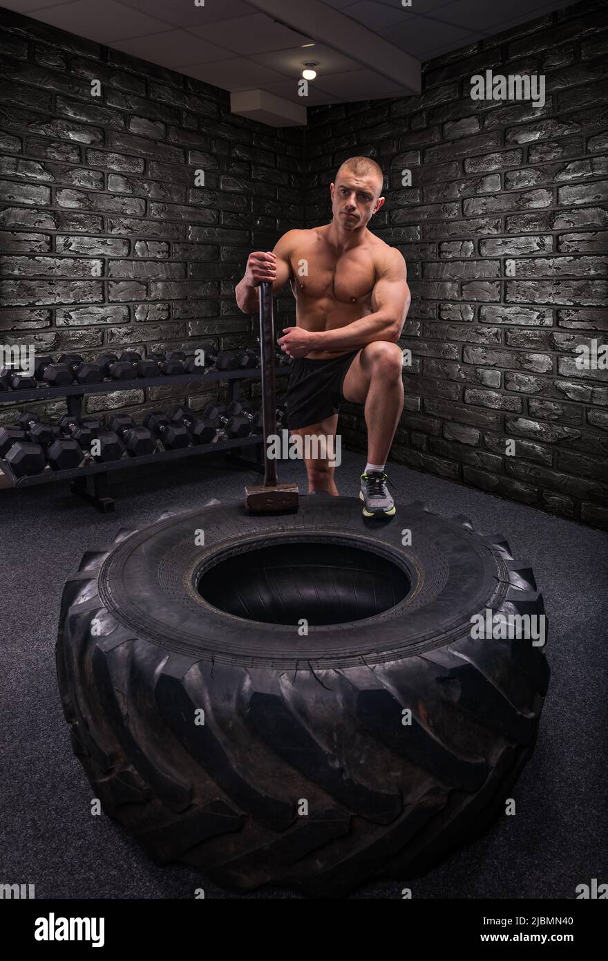 Bodybuilder with hammer and huge wheel in a gym Stock Photo - Alamy