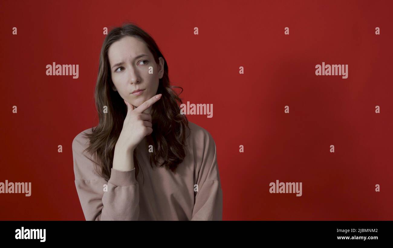 Portrait of a thoughtful young woman with long hair, thinking intensely ...
