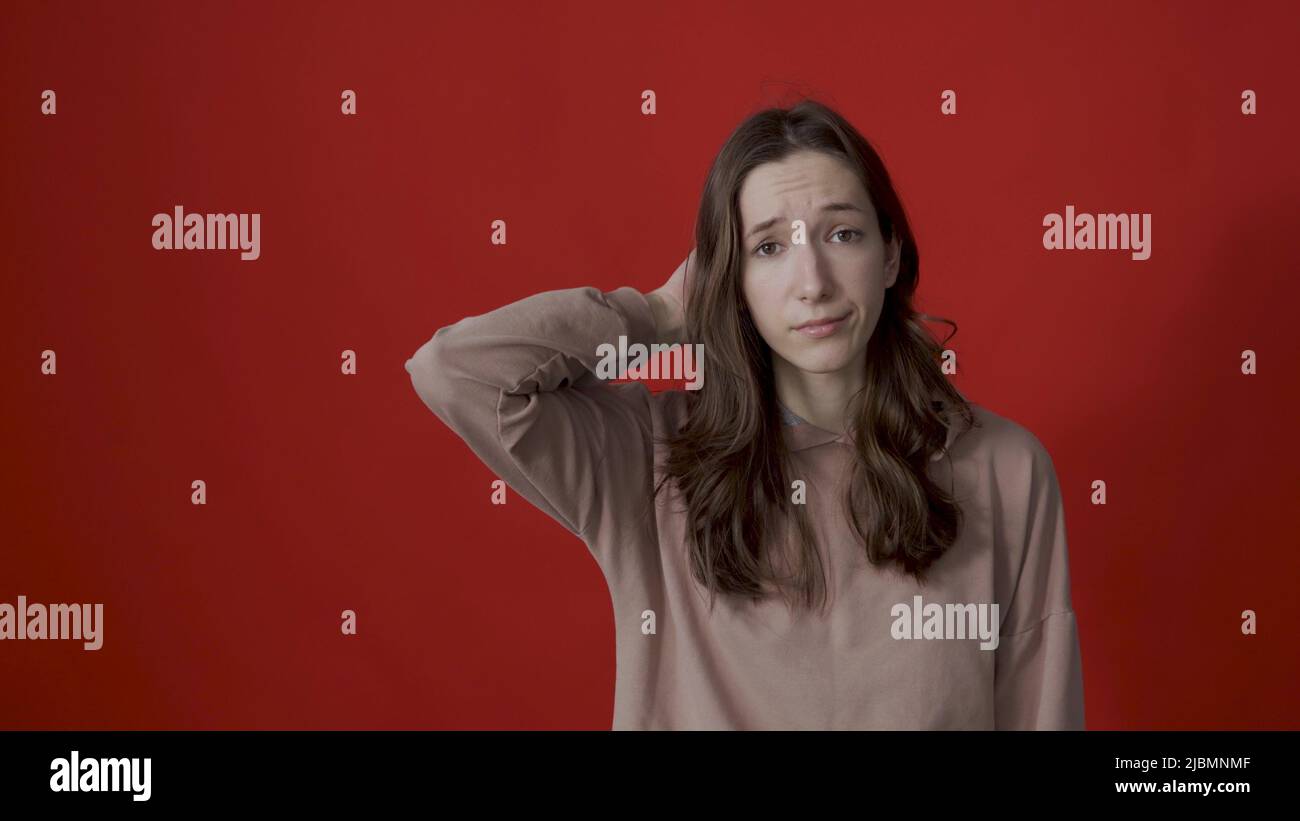 Portrait of a thoughtful young woman with long hair, thinking intensely ...