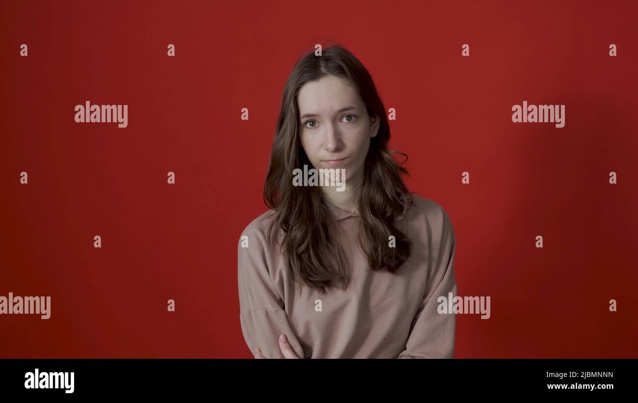 Portrait of a thoughtful young woman with long hair, thinking intensely ...