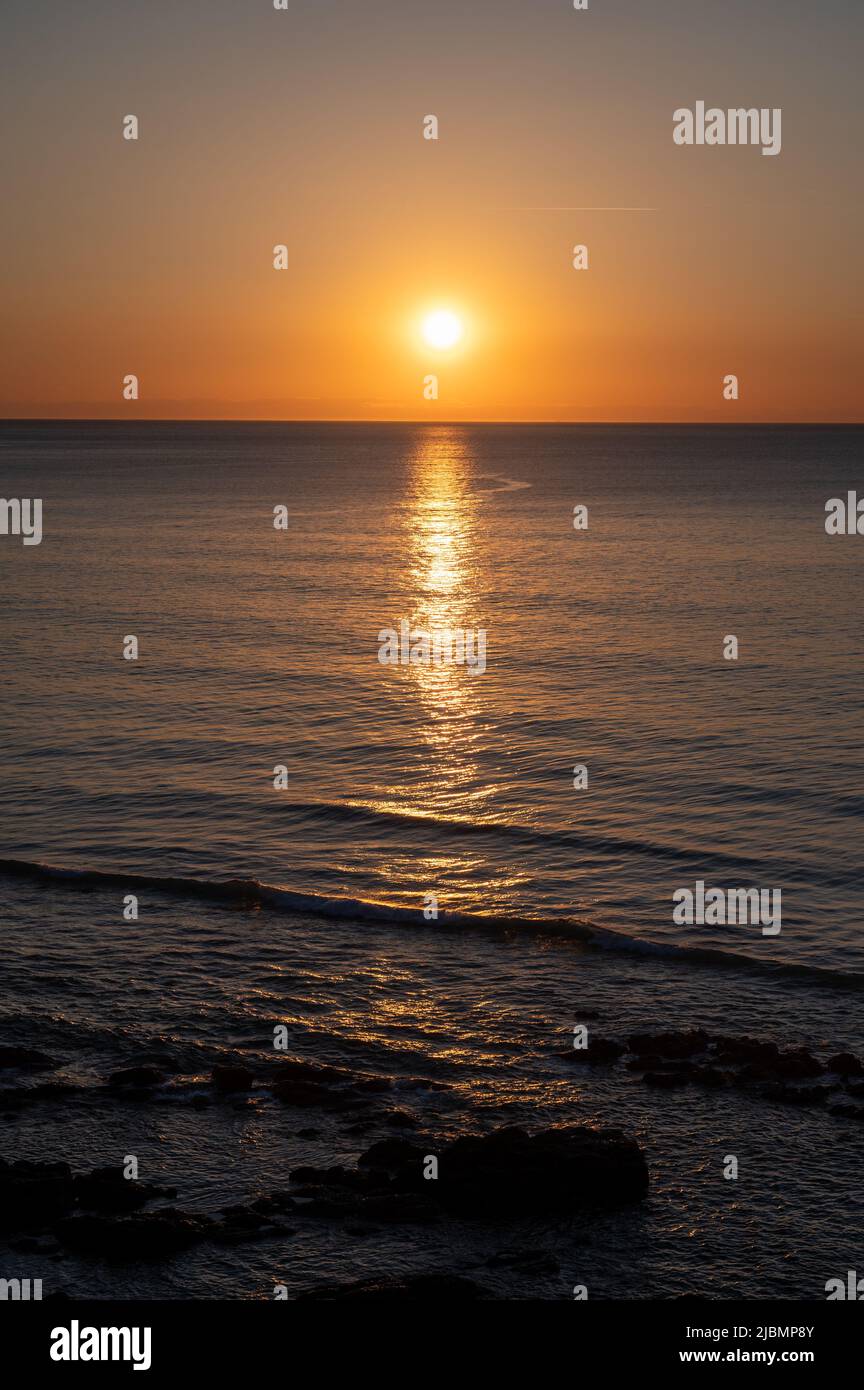 Sunset in calm waters of Atlantic ocean and clear sky with reflection ...