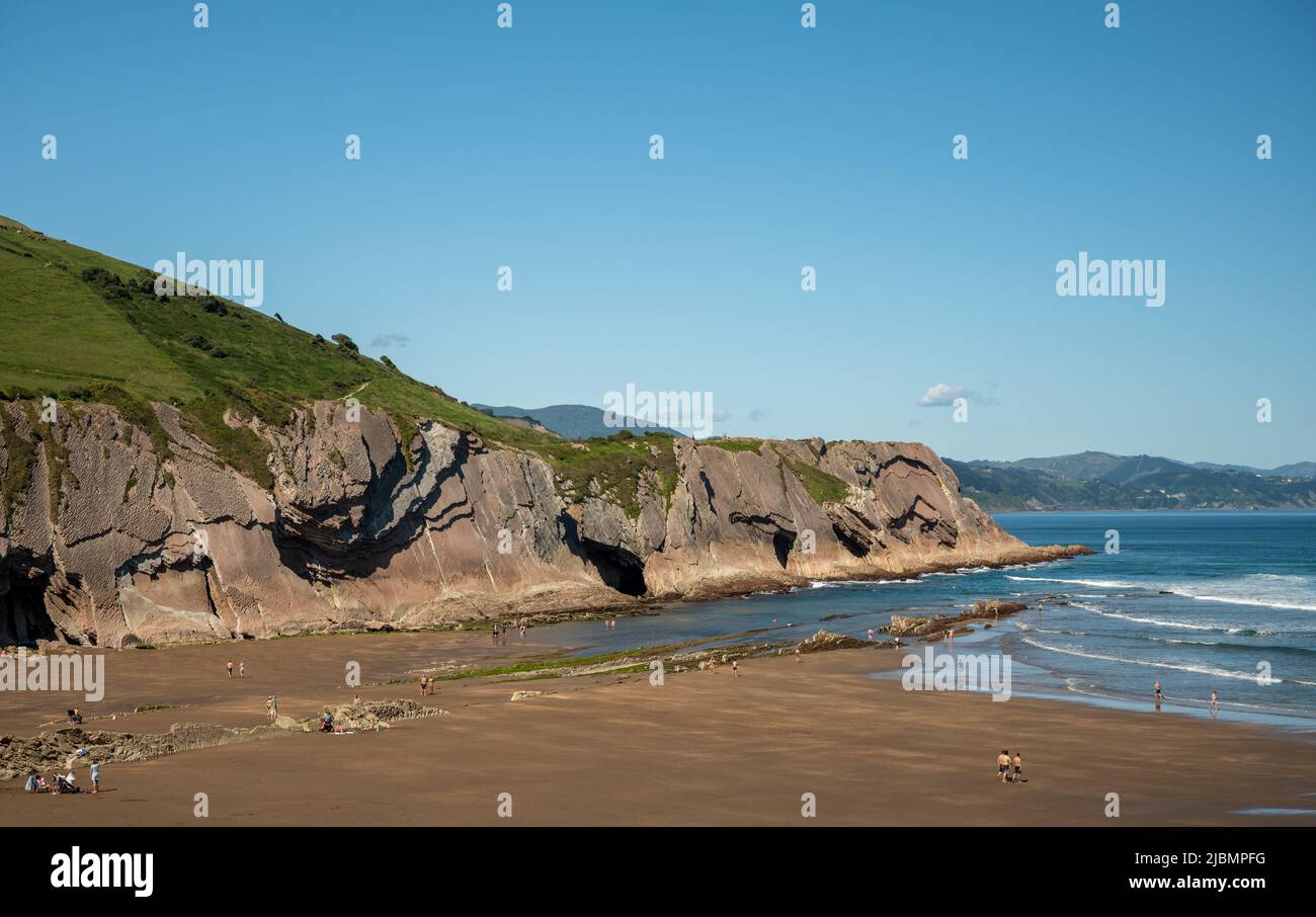 View on sandy beach near steeply-tilted layers of flysch geological ...