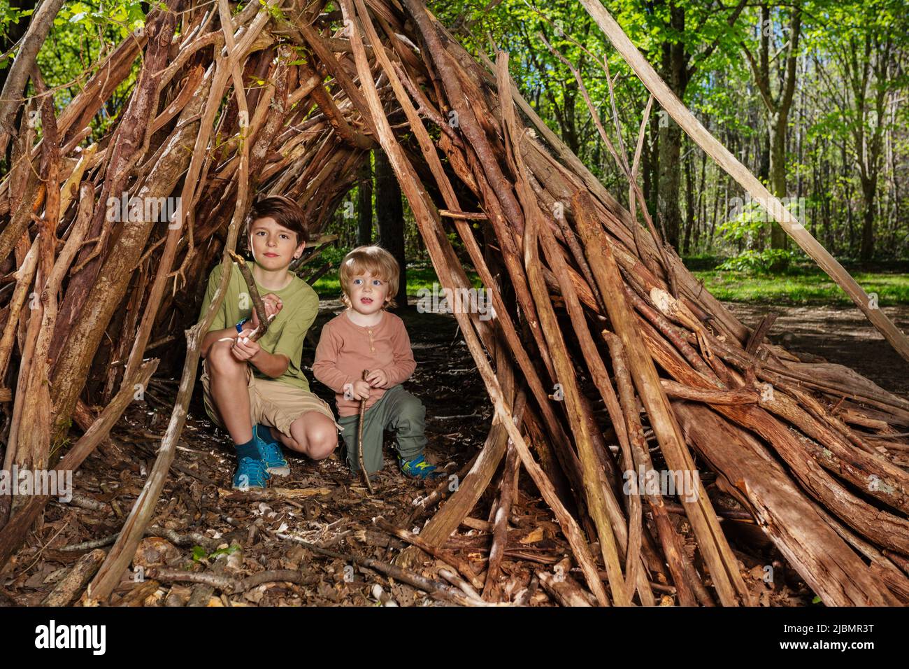 Two boys play build hut of branches in the forest Stock Photo - Alamy
