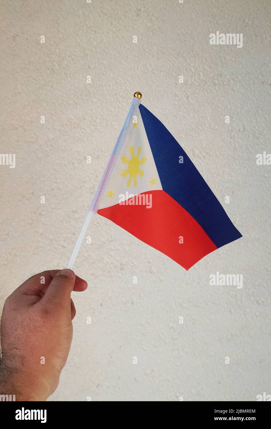 A hand waves a Philippine flag against a white background Stock Photo ...