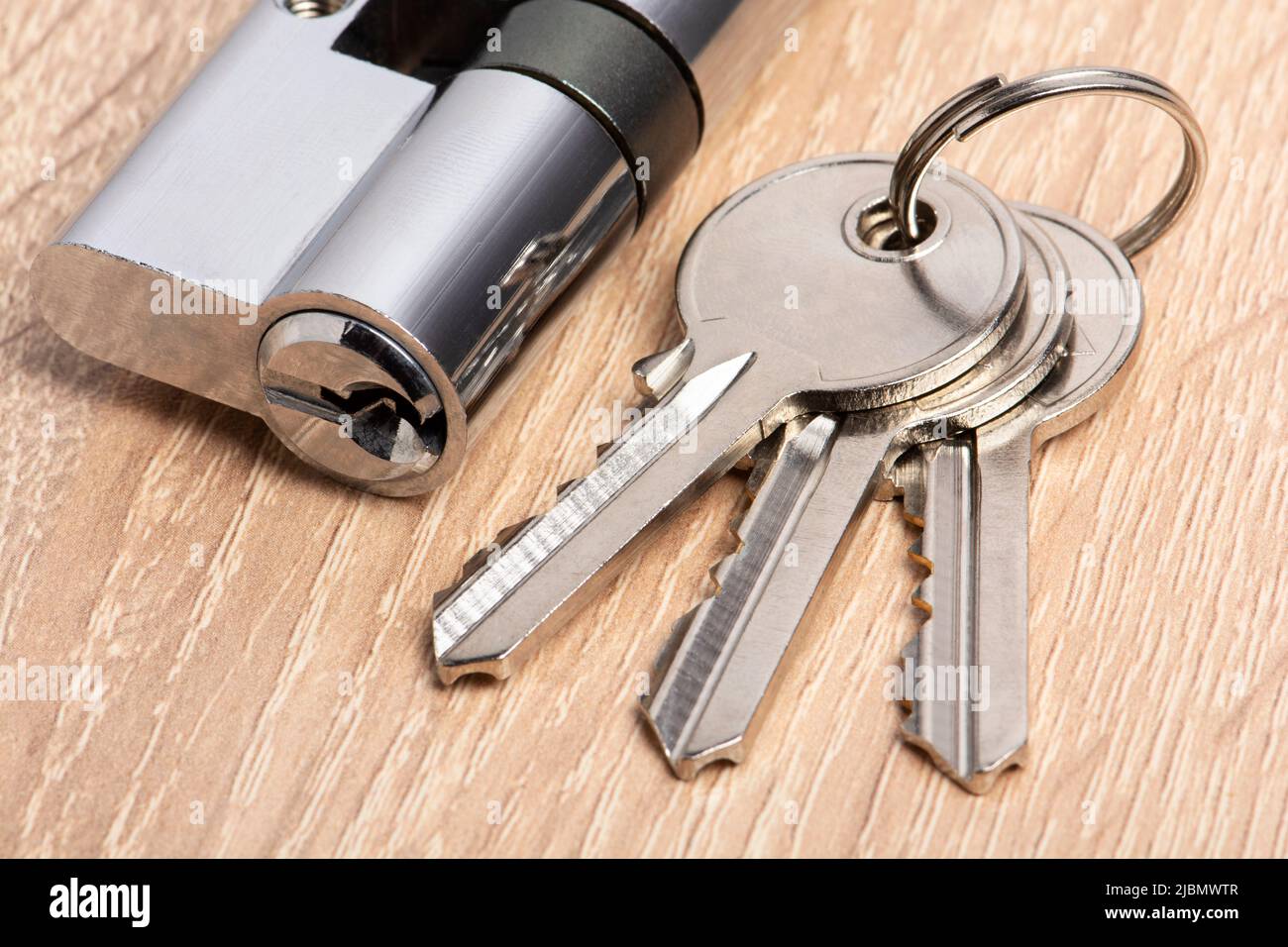 Door lock on wooden background. Key cylinder with keys Stock Photo - Alamy
