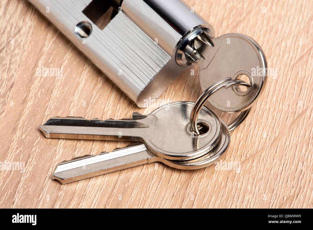 Door lock on wooden background. Key cylinder with keys Stock Photo - Alamy