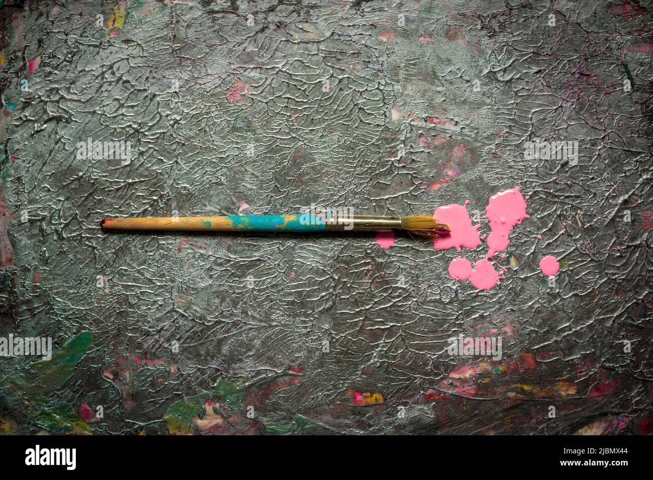 Old brush on paper with dark and silver textured paint with drops of ...