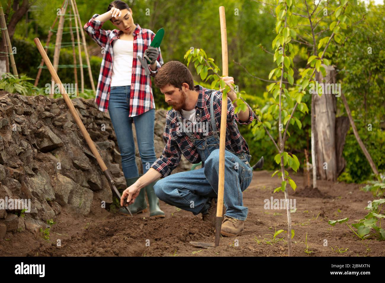 Young and happy farmer's couple at their garden in sunny day. Man and ...