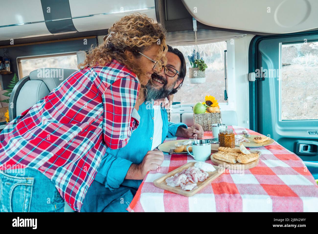 Happy traveler couple hug with love and fun together inside a camper ...
