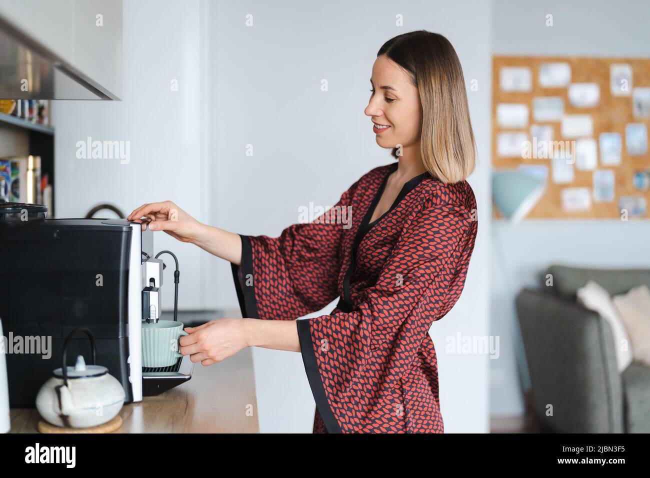 Woman using coffee machine to make big mug of coffee at home. Woman ...