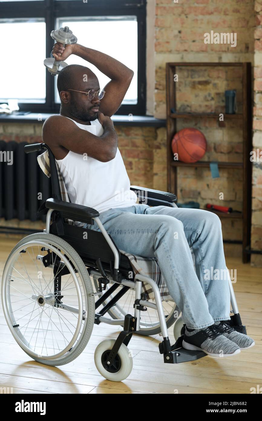 African American man with disability training with dumbbells sitting in ...