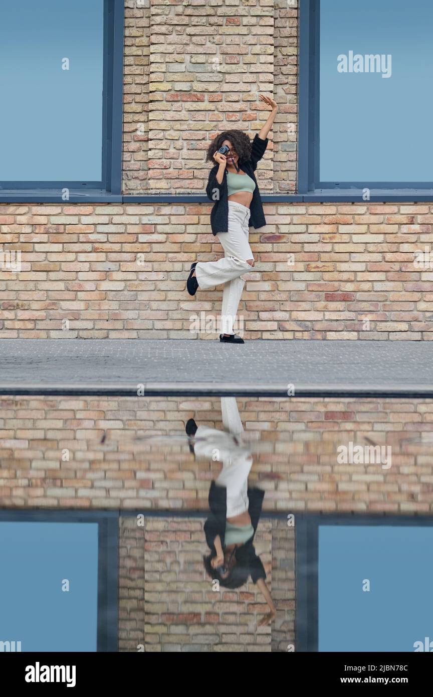 Woman with camera in front of brick building Stock Photo - Alamy