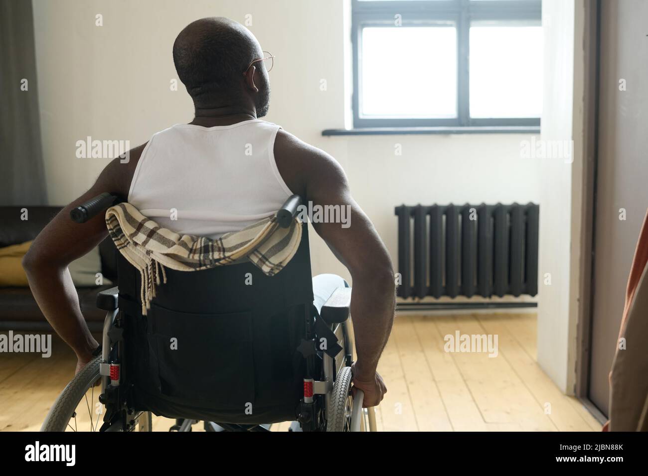Rear view of African young man with disability sitting in wheelchair in ...