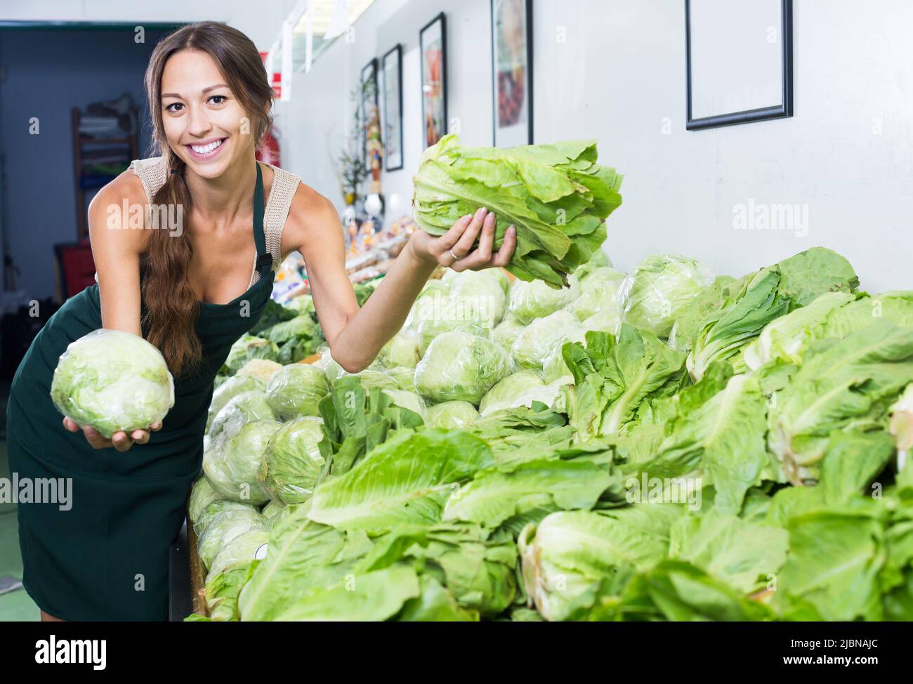 Female seller wearing apron holding fresh cabbage head Stock Photo - Alamy
