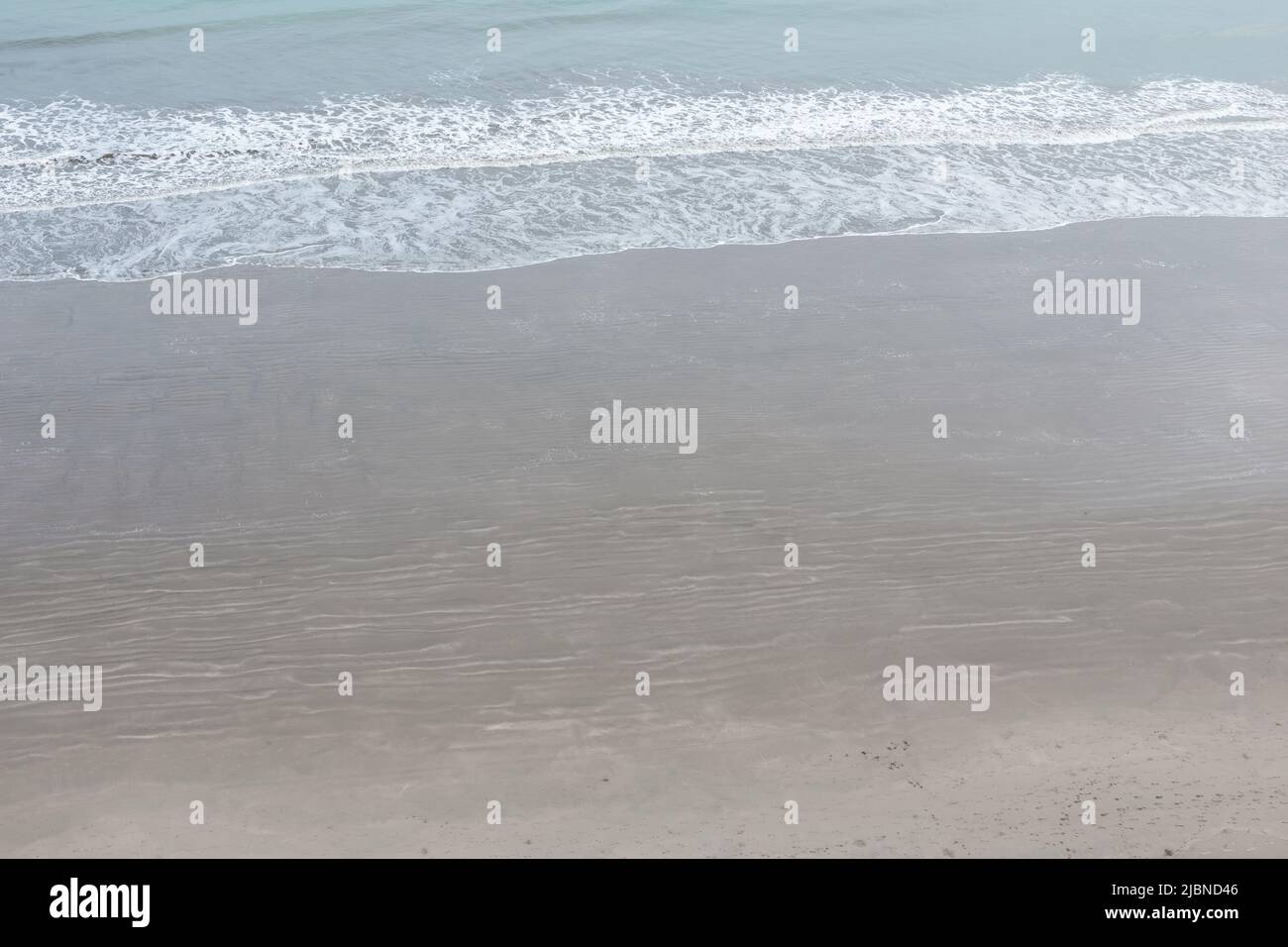 details of the edge of the sea with wet sand and ocean with breaking ...