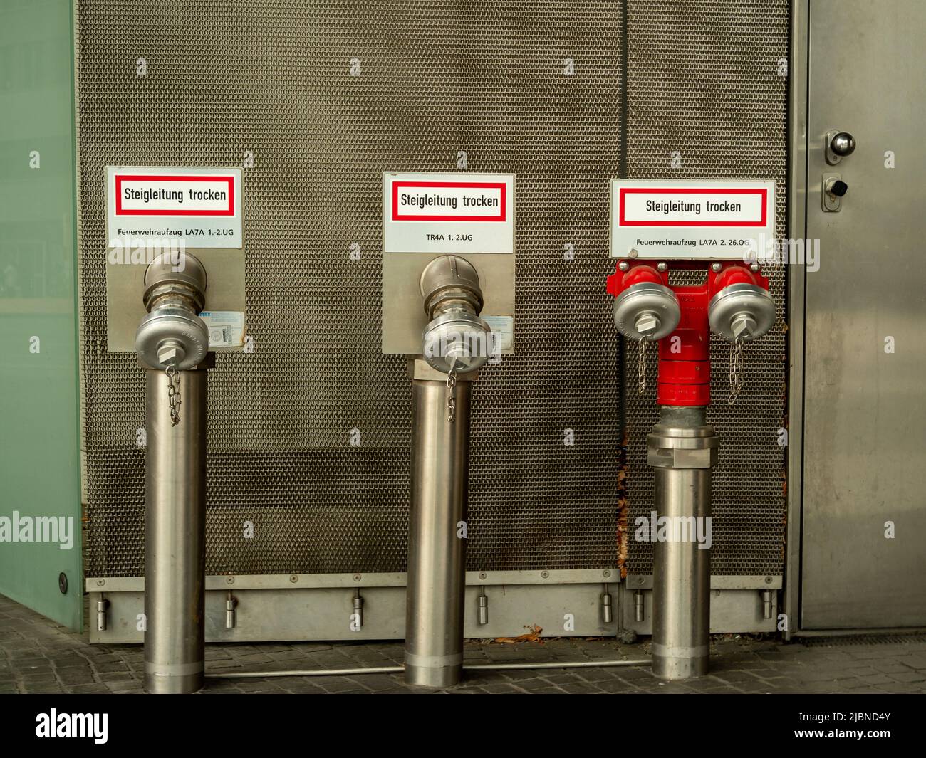 Fire hydrant at the building. Red hydrant Stock Photo - Alamy