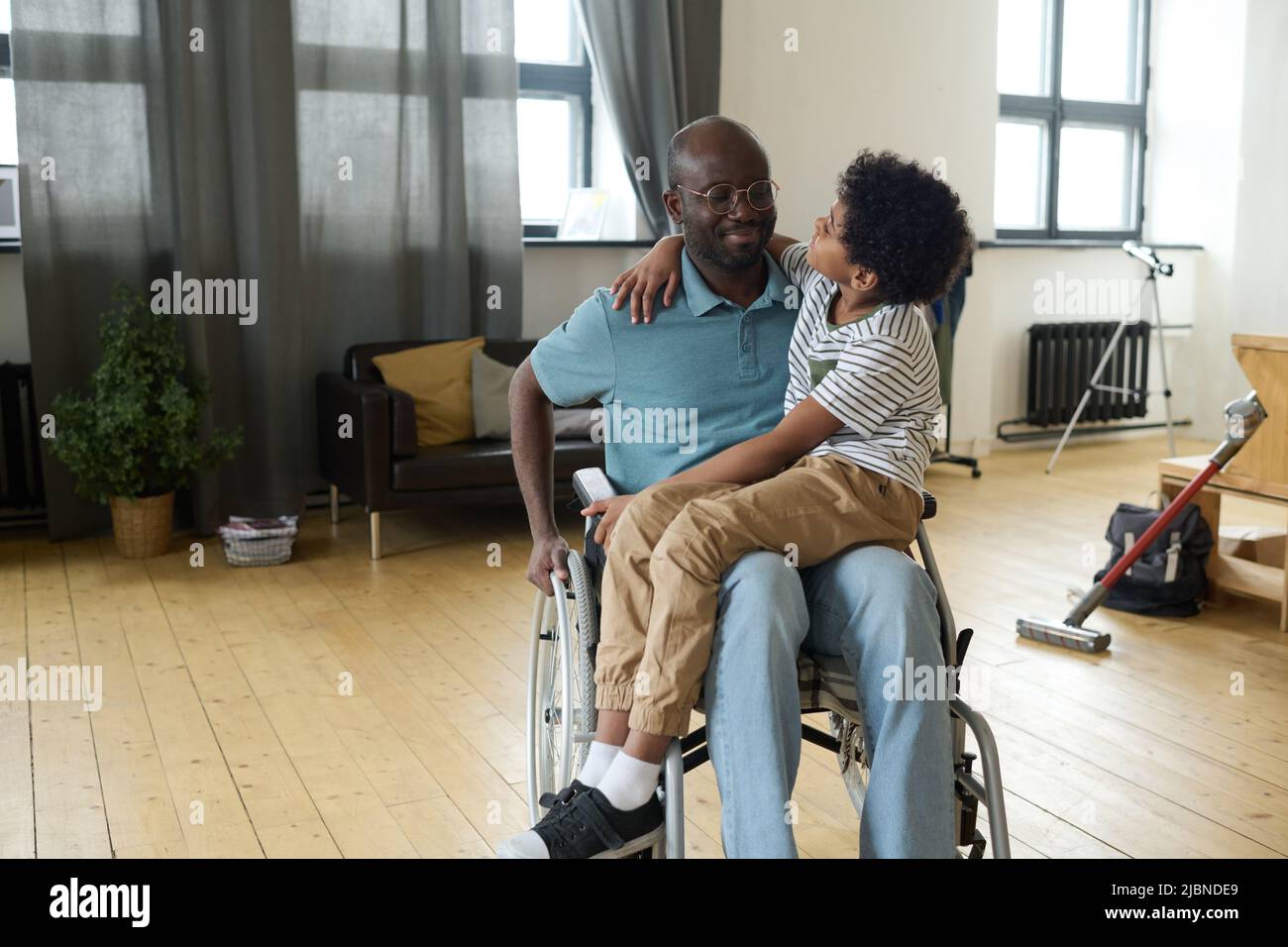 African disabled father sitting in wheelchair with little son on his ...