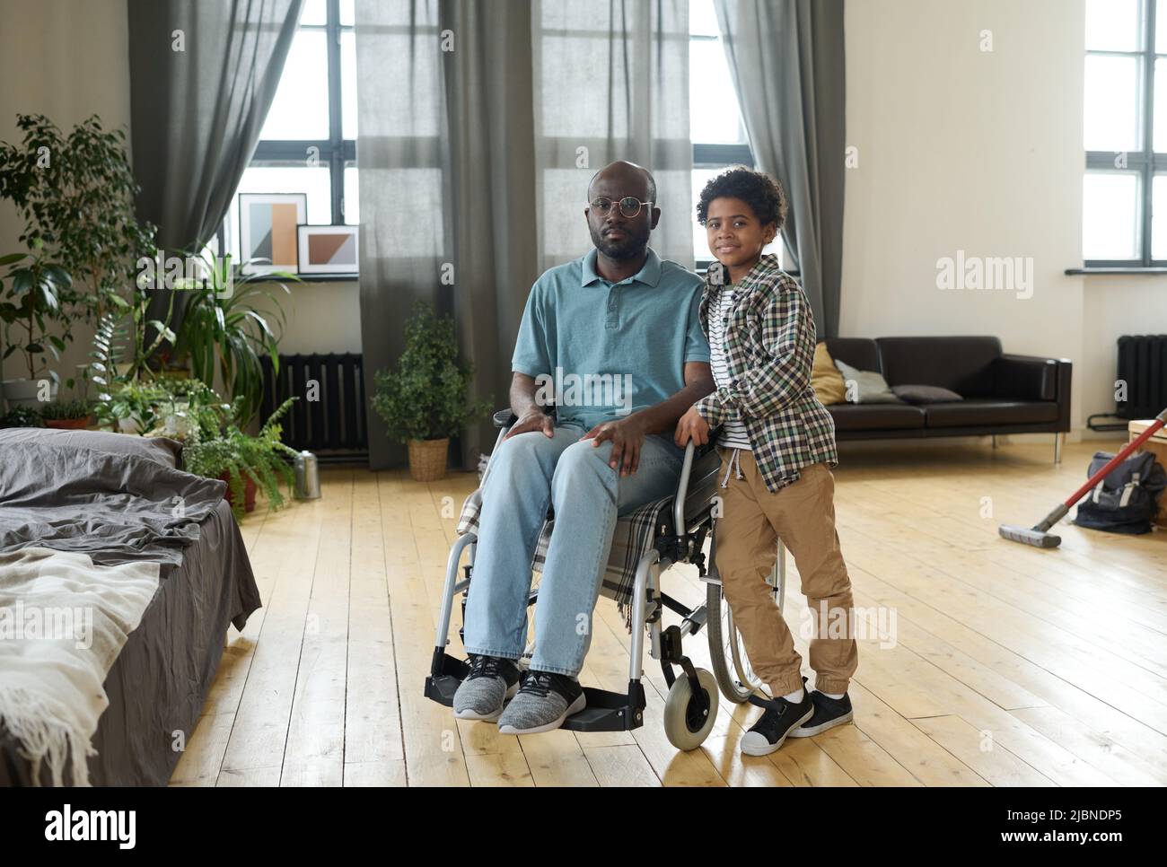 Portrait of African disabled father sitting in wheelchair and looking ...