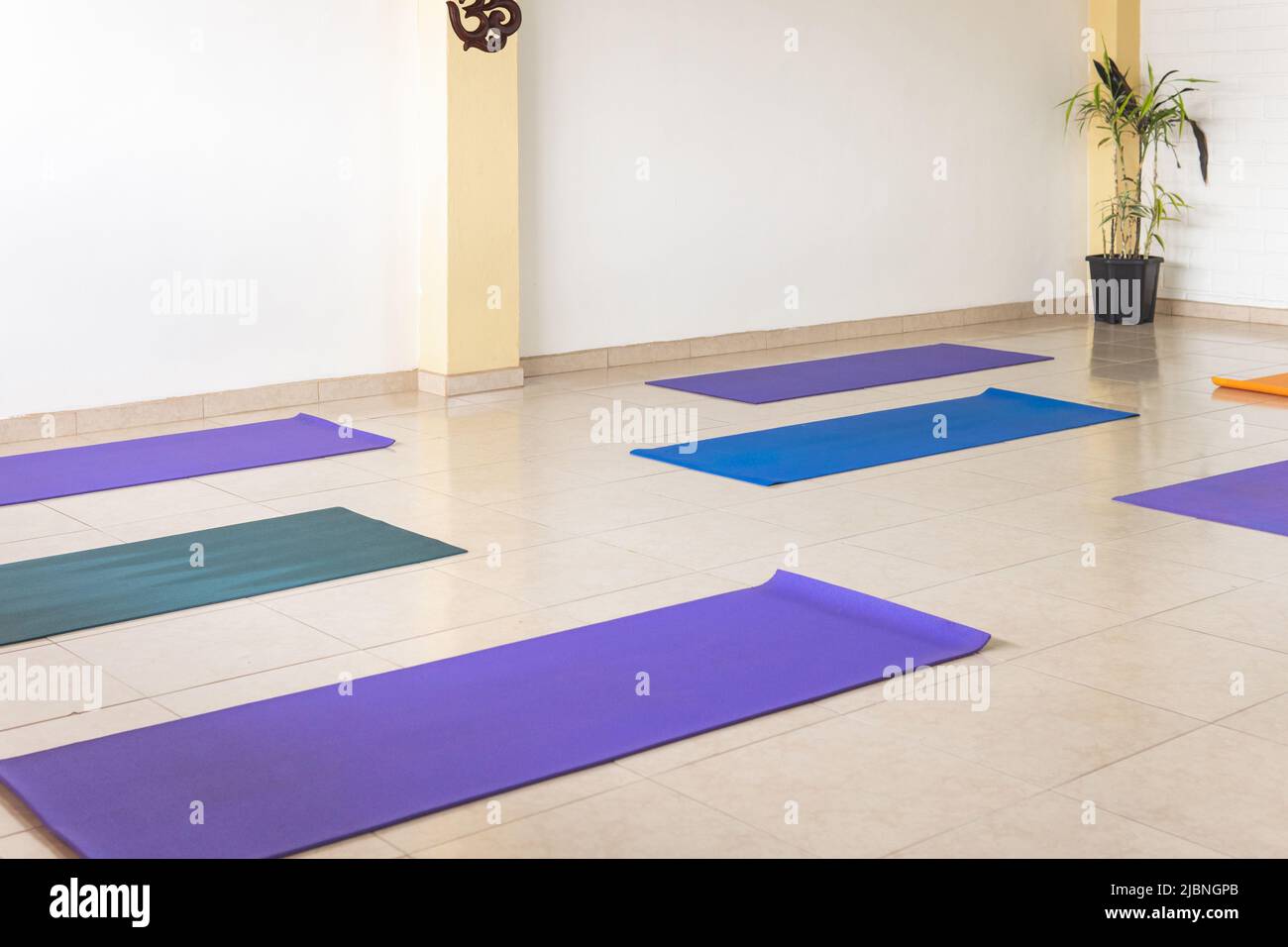 Yoga room with colorful mats on the floor and detail of Om sign on the ...