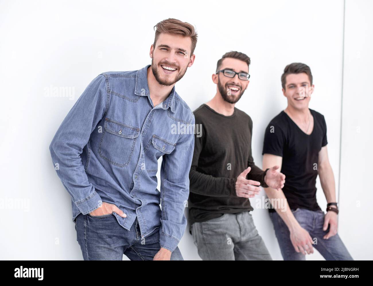 three people leaning against the wall, smiling Stock Photo - Alamy