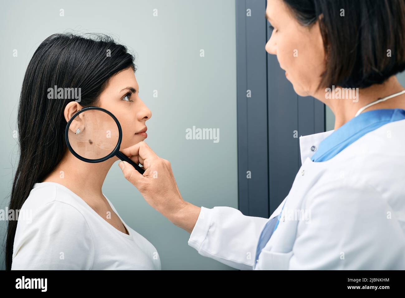 Mole dermoscopy, preventive of melanoma. doctor examining woman's neck ...