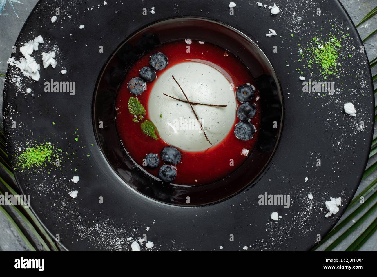 Panna cotta with raspberry sauce in a black plate Stock Photo - Alamy