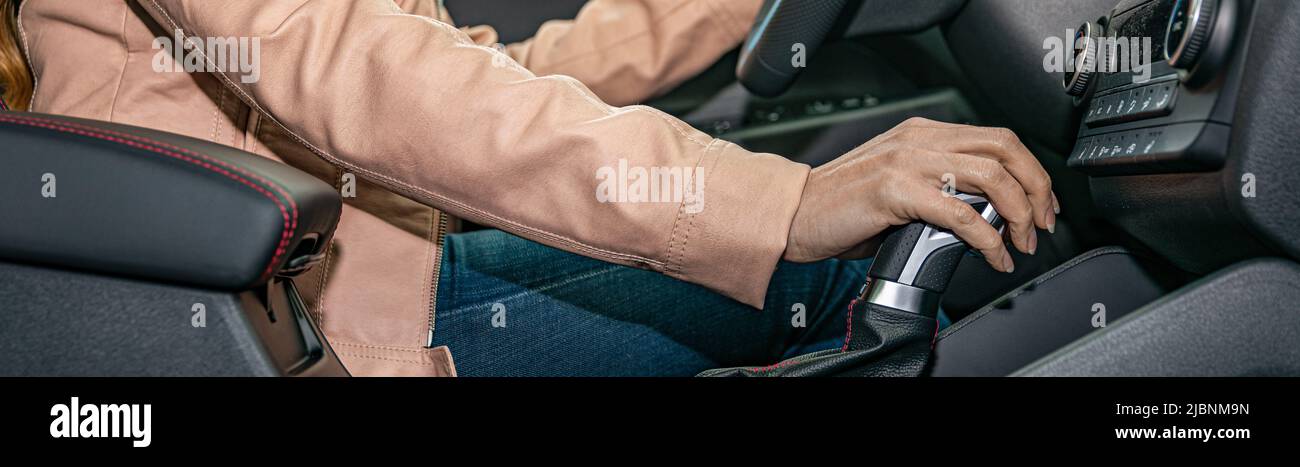 panoramic view of a female driver pulling a gear lever in a modern car ...