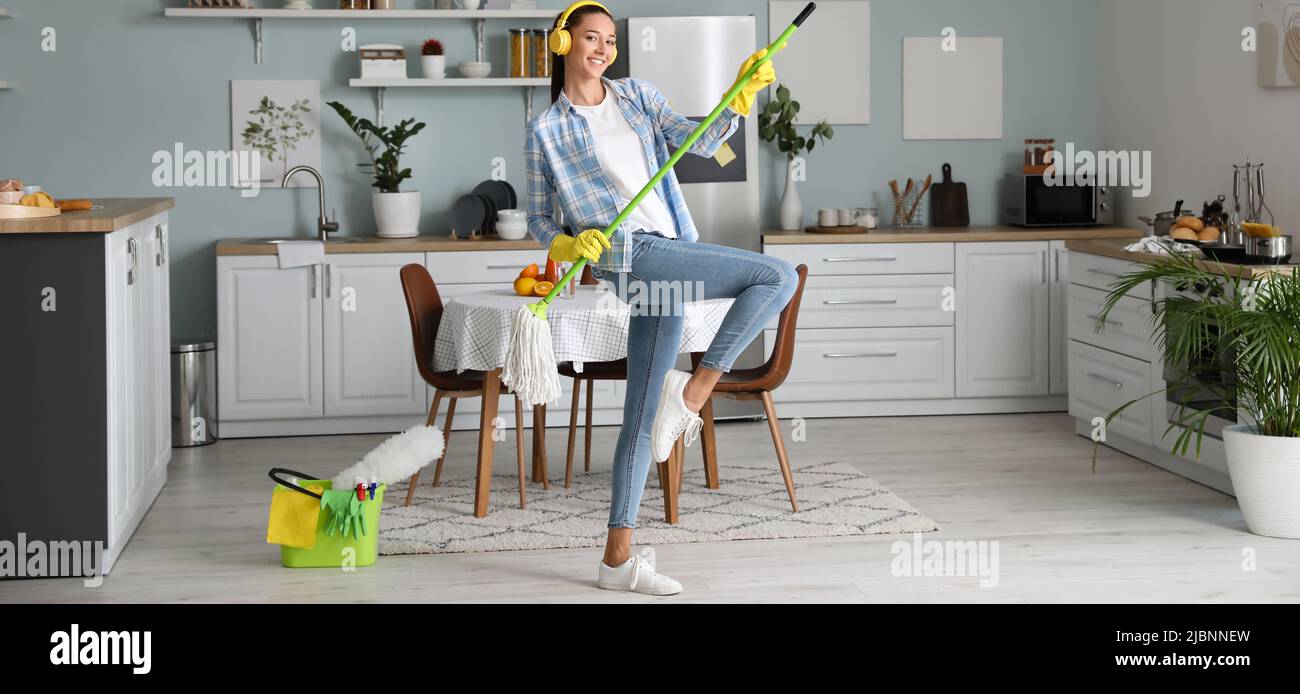 Young woman having fun while cleaning kitchen Stock Photo - Alamy