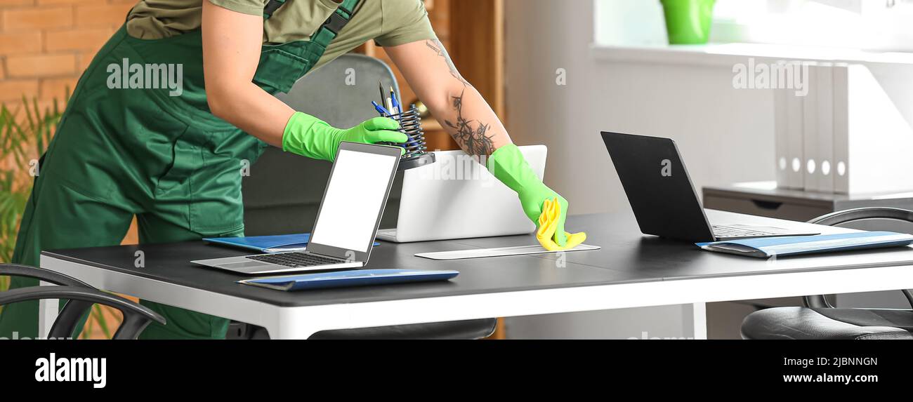 Male janitor wiping dust from table in office Stock Photo - Alamy