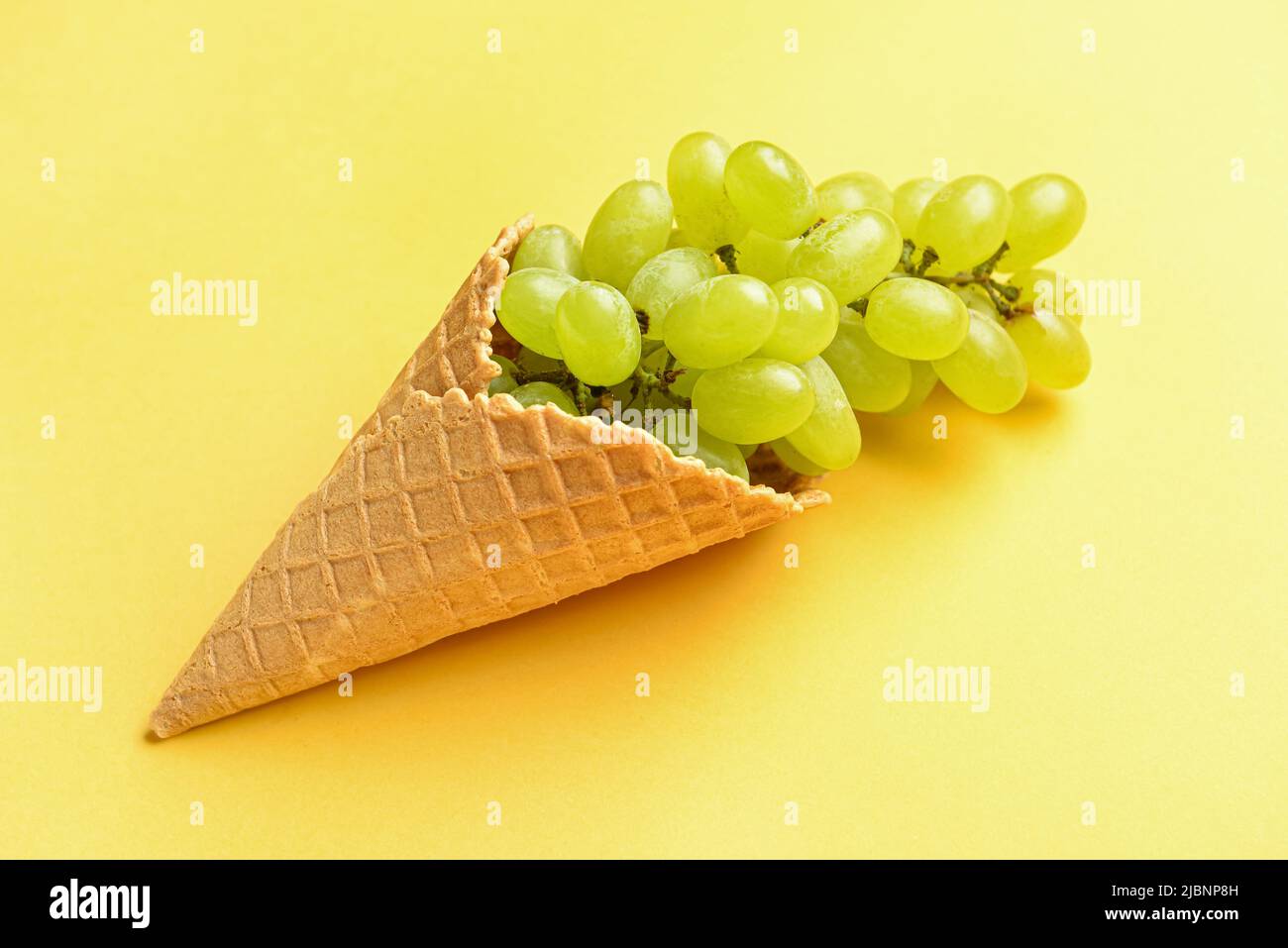 Wafer cone with fresh grapes on color background Stock Photo - Alamy