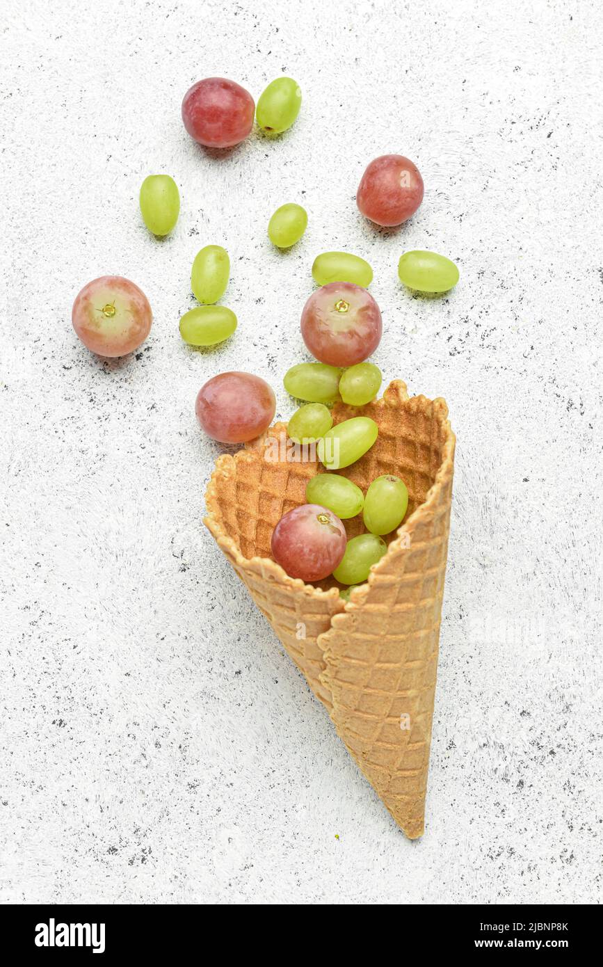 Wafer cone with fresh grapes on light background Stock Photo - Alamy