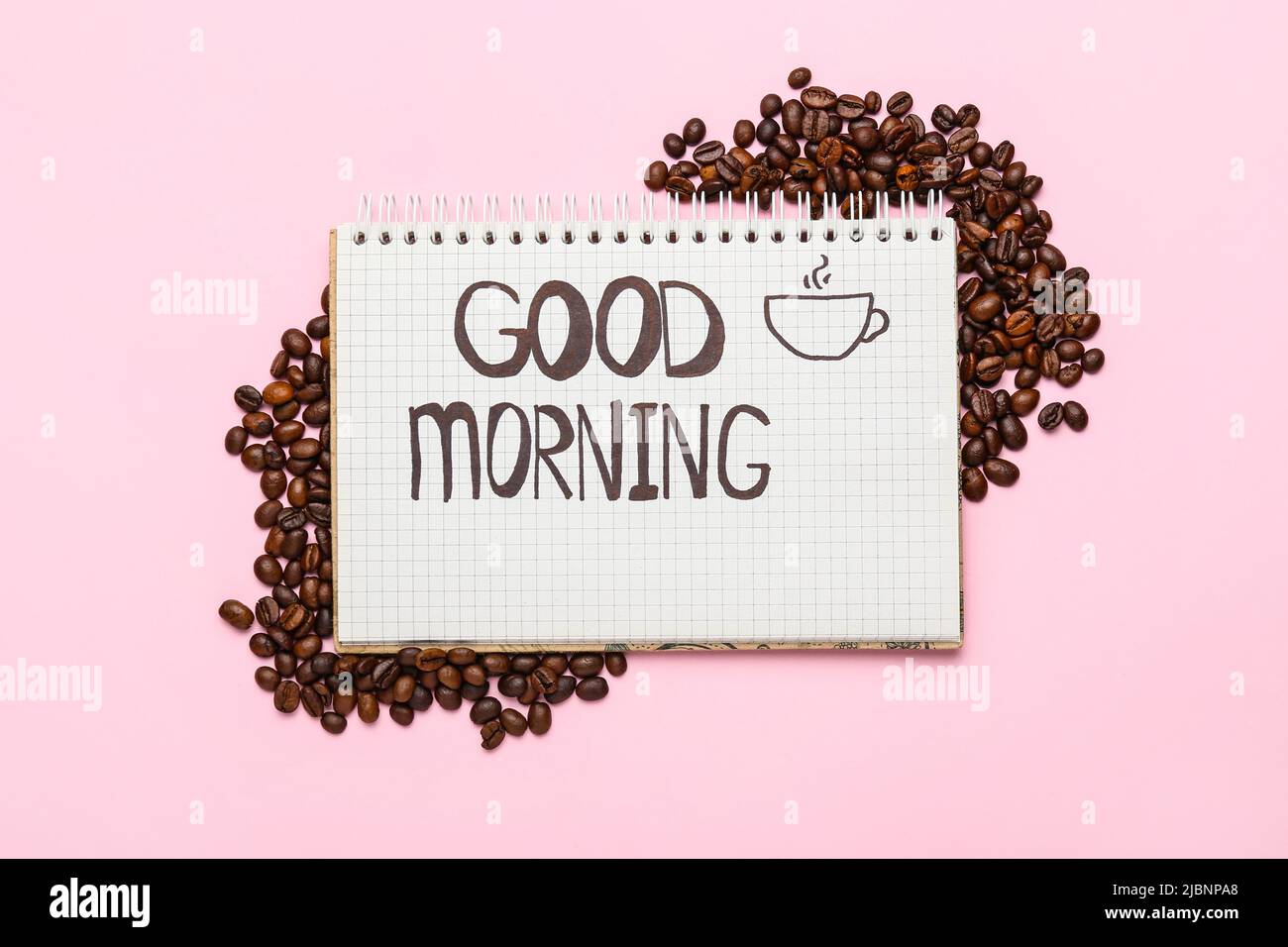 Notebook with text GOOD MORNING and coffee beans on pink background ...