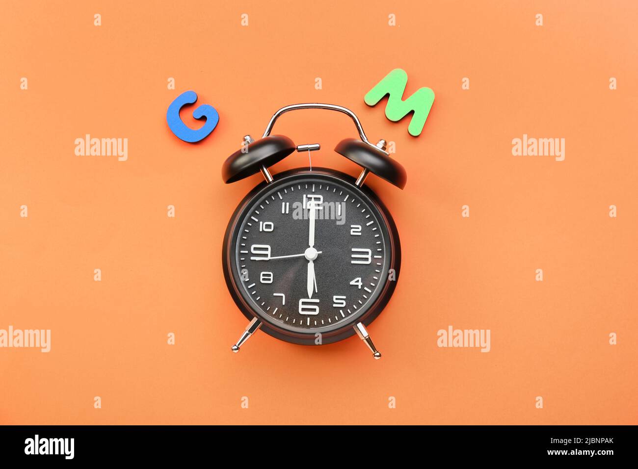 Alarm clock and letters GM on color background Stock Photo - Alamy