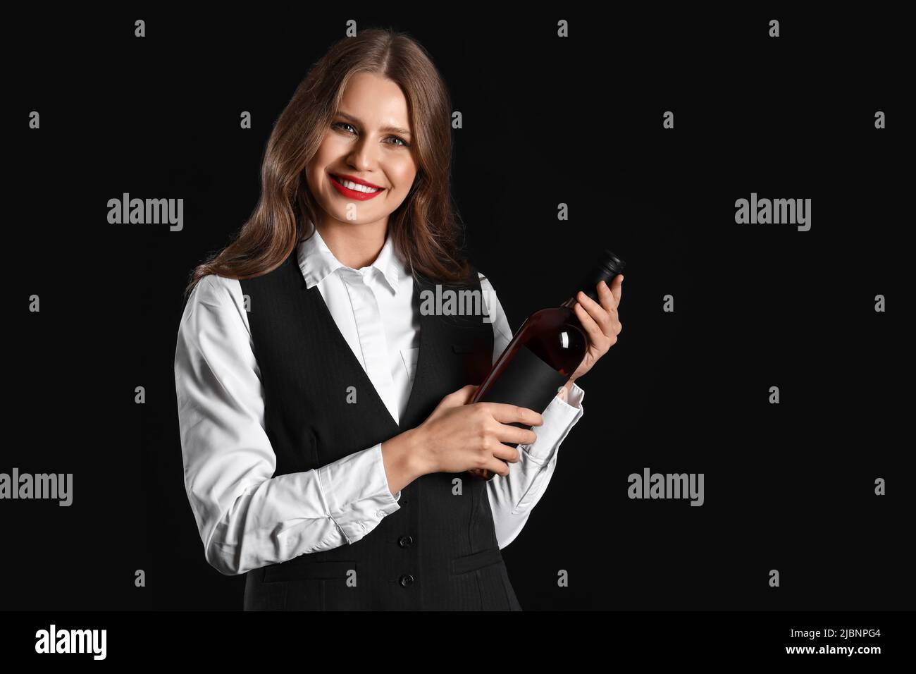 Beautiful female sommelier with bottle of wine on black background ...